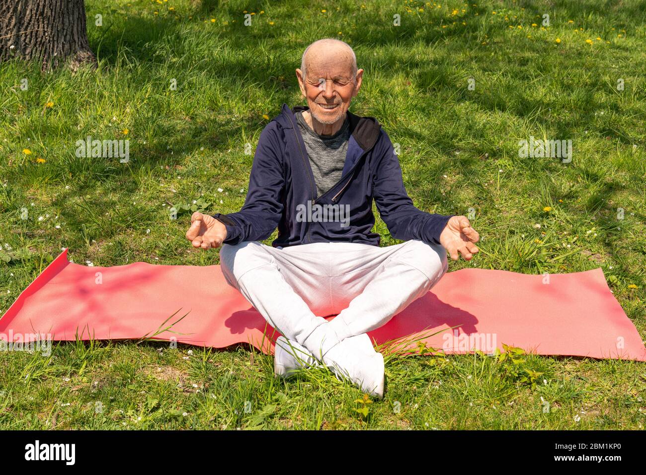 Sporty old man sitting on the yoga mat in lotus position, meditation ...