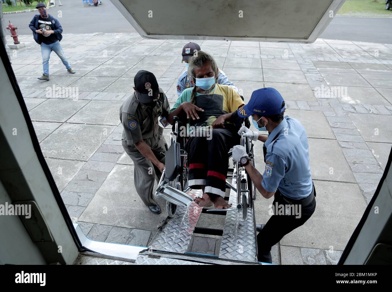 An elderly homeless man wearing a face mask as a preventive measure is ...