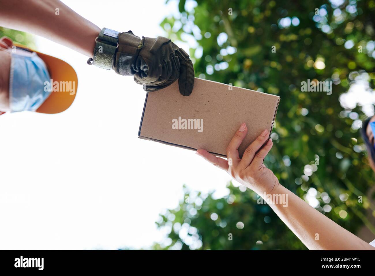 Delivery man in medical mask giving small cardboard box to customer ...