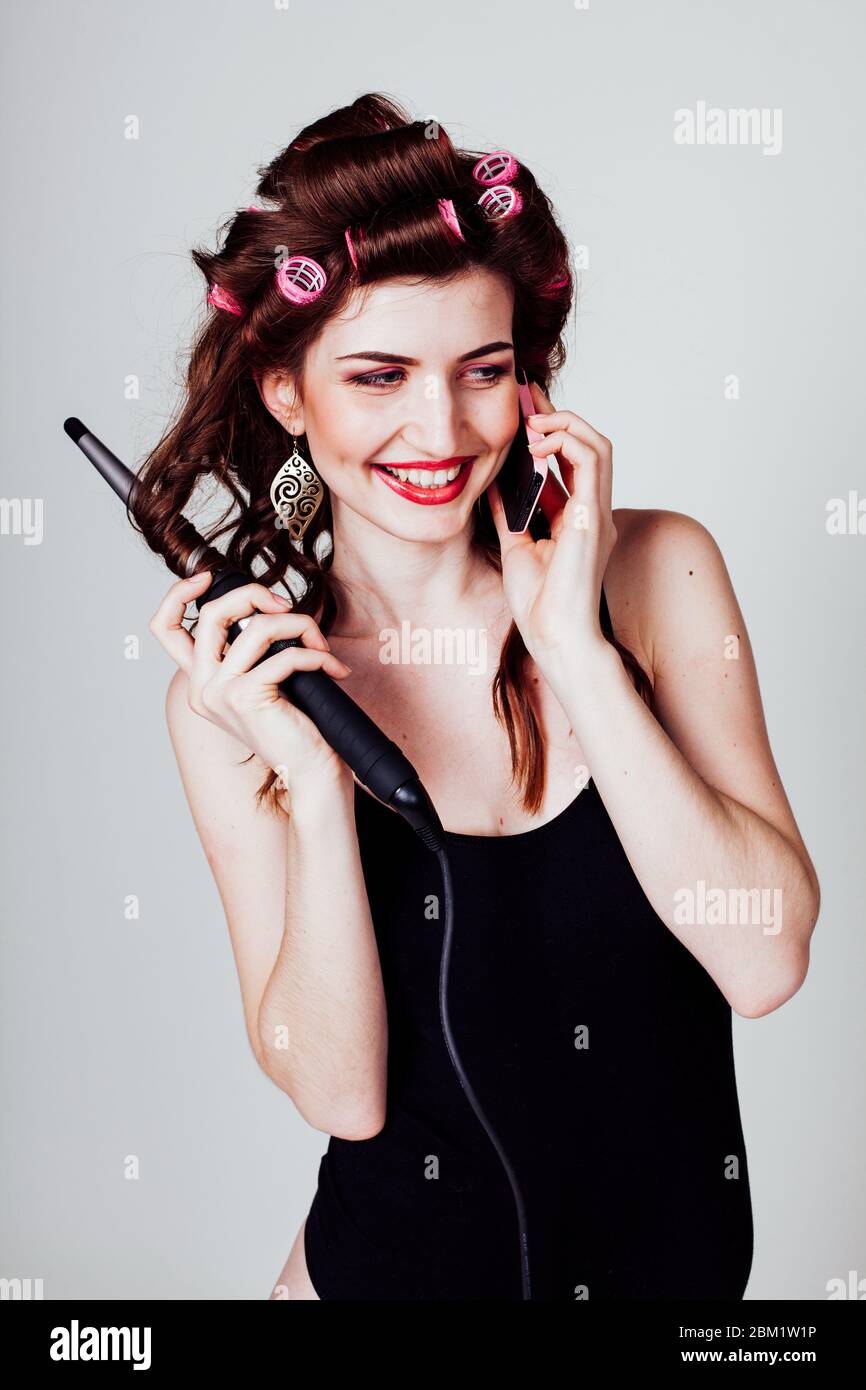 girl with hair curlers talking on the phone and makes the hairstyle ...