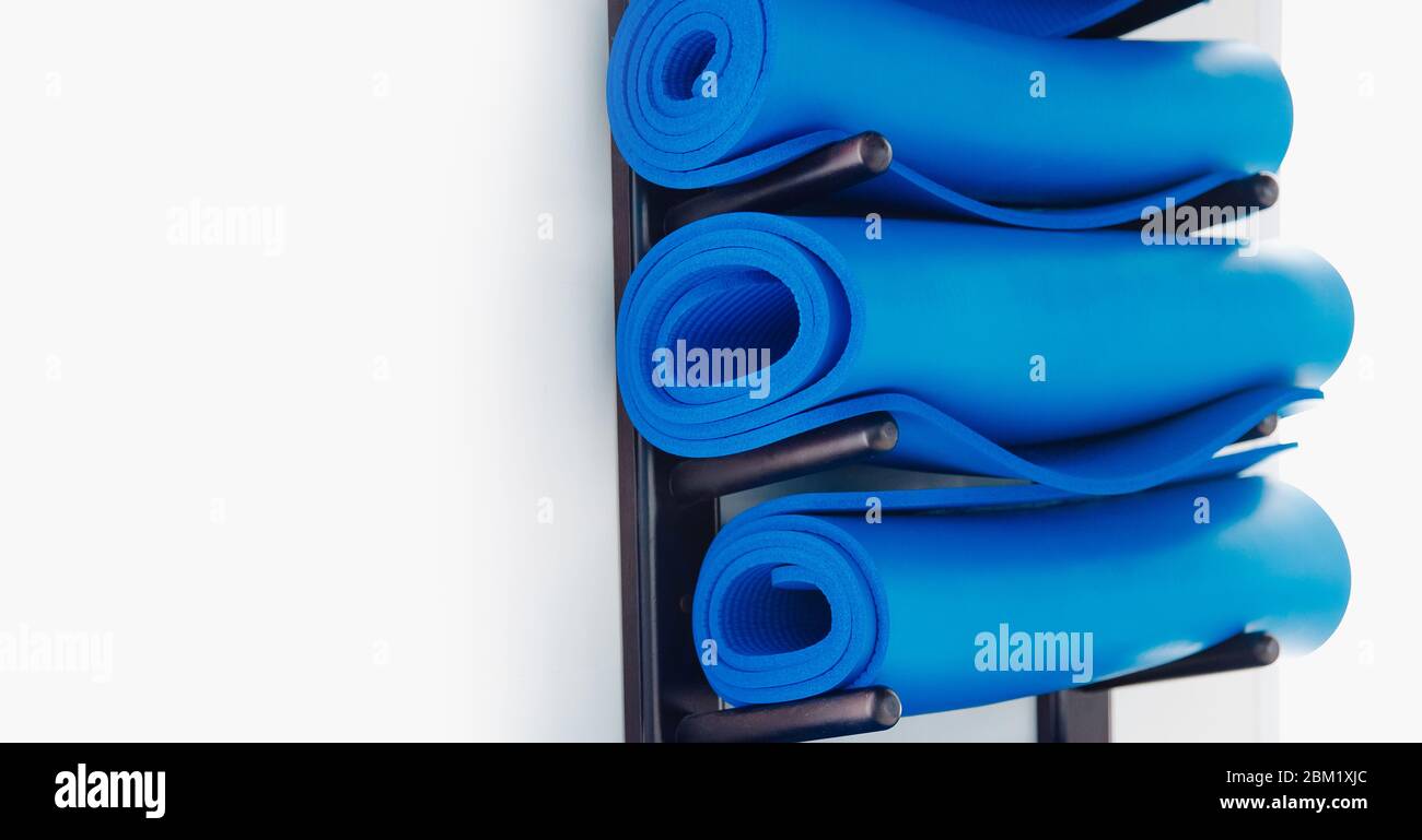 Blue yoga mat attached white wall in stack. Concept tool for practicing ...