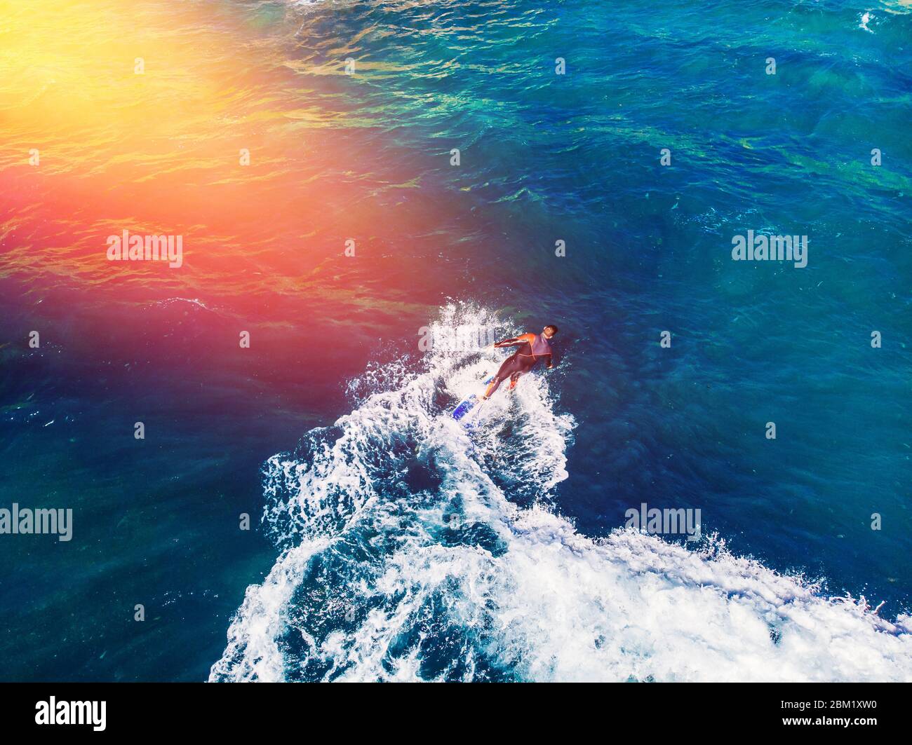 Surfer rows up to catch crest of wave in blue ocean. Concept surfing ...