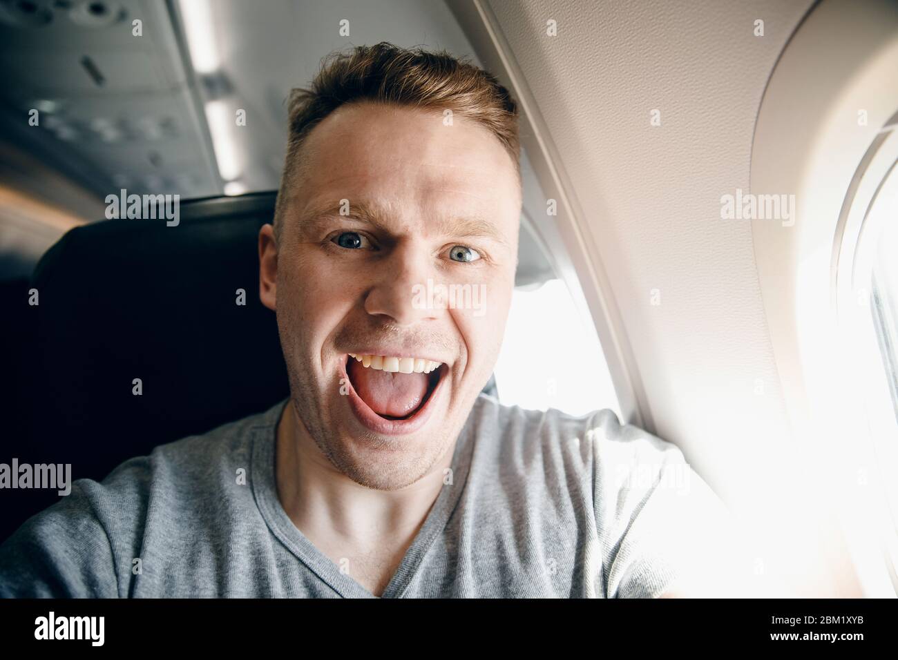 Man smiles and takes selfie photo on plane aircraft. Travel concept ...