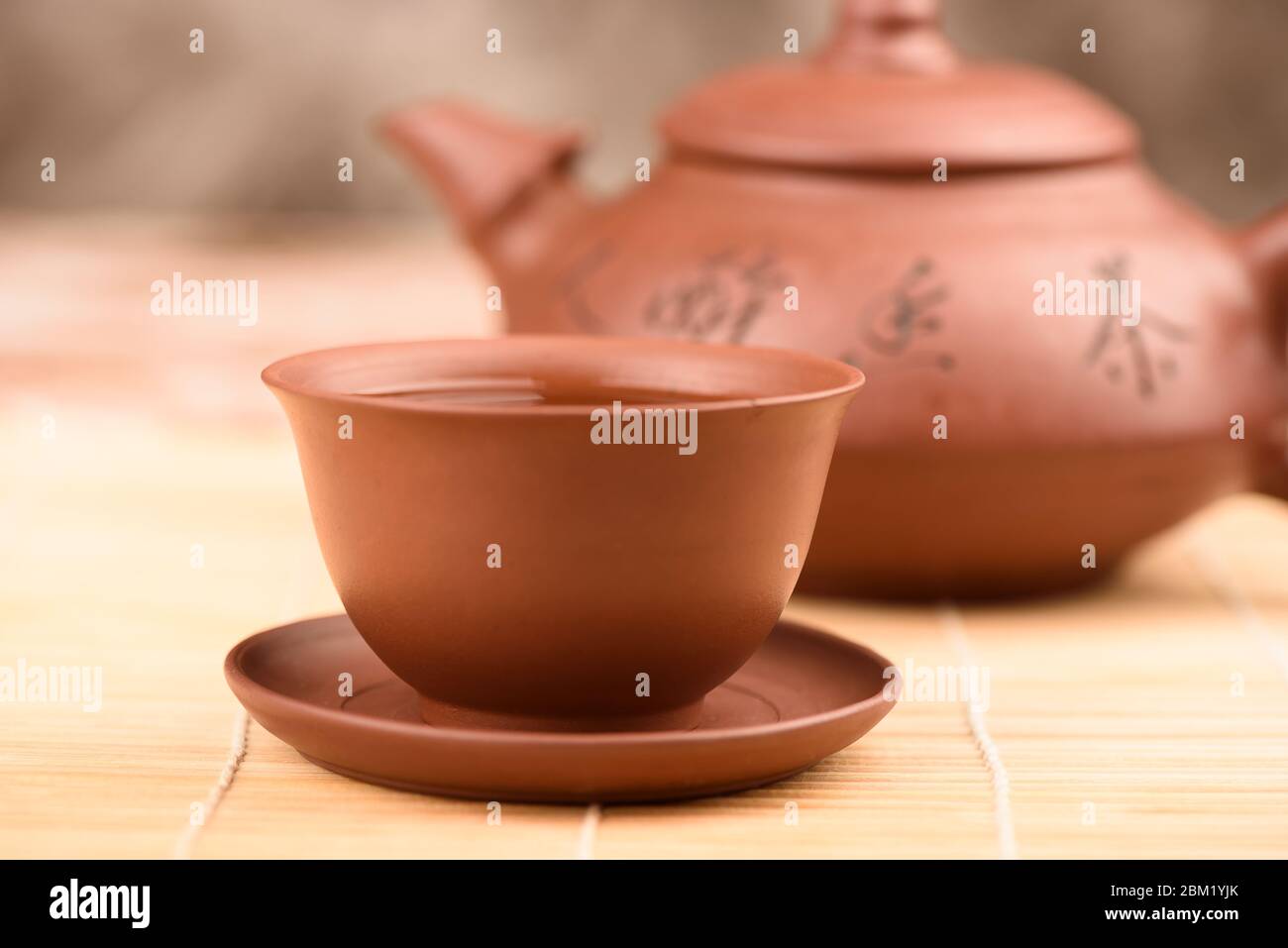 Selective focus. Clay bowl with green tea on a clay saucer. Close up ...