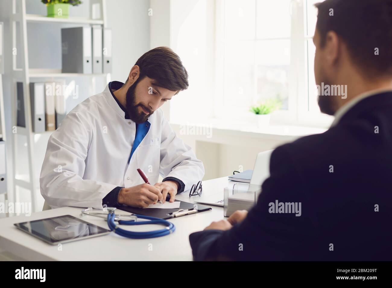 Patient visiting doctor at clinic office. Medical work writes a ...