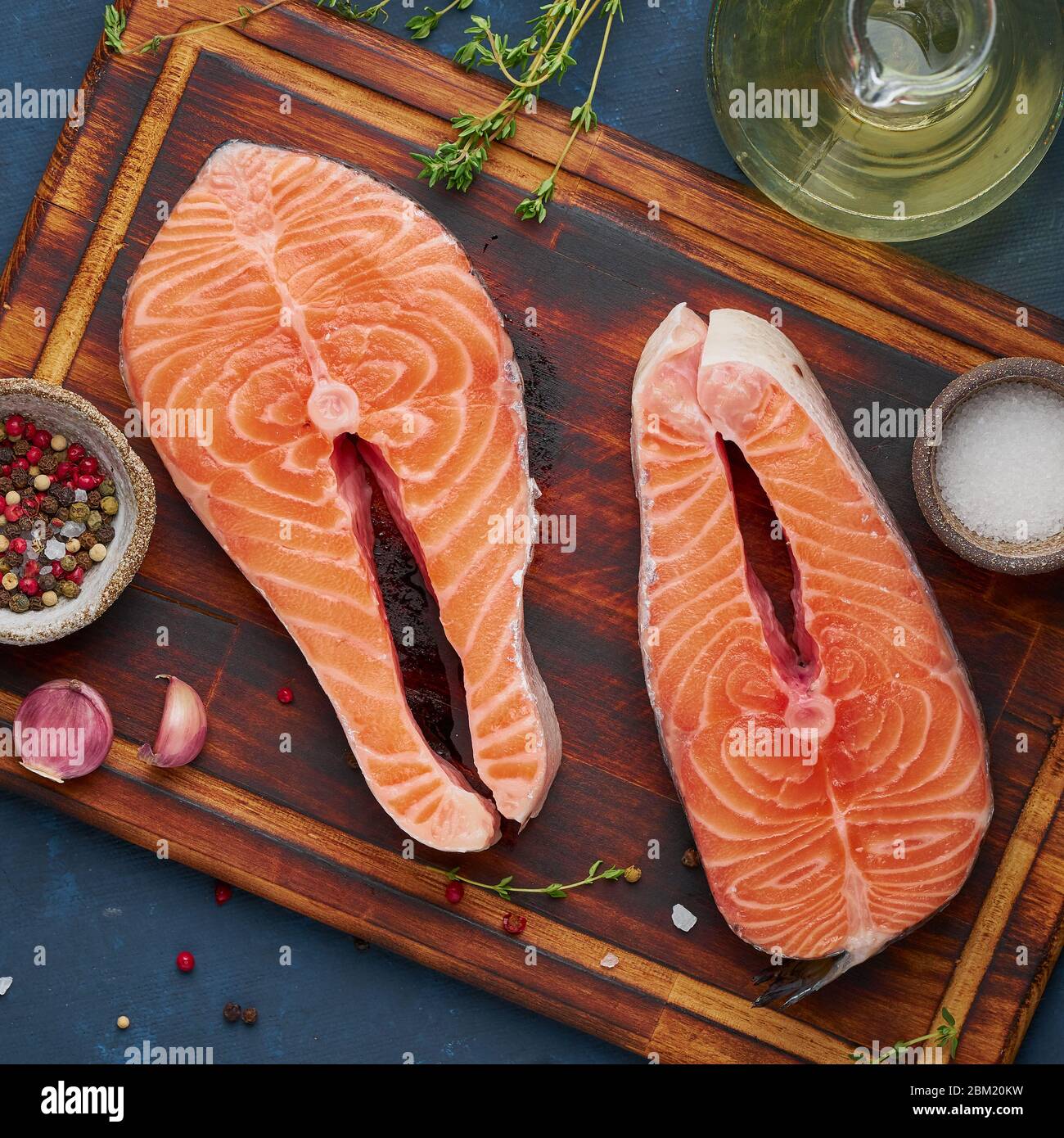 Two salmon steaks, fish fillet, large sliced portions on chopping board ...