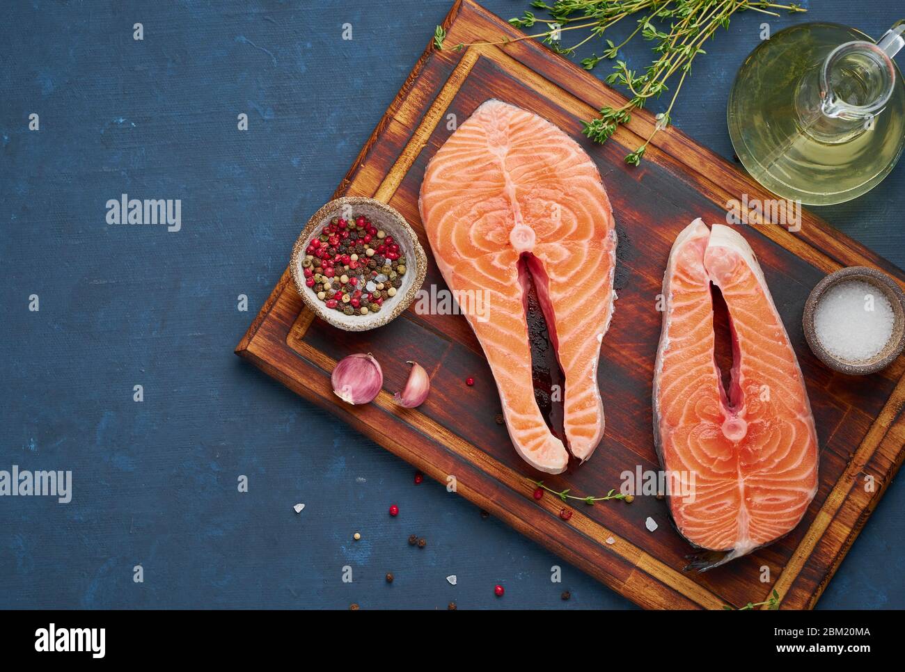 Two salmon steaks, fish fillet, large sliced portions on chopping board ...
