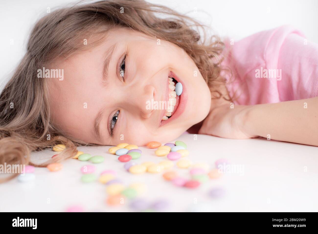 Children and chocolate. A cheerful girl plays and eats chocolate multi ...