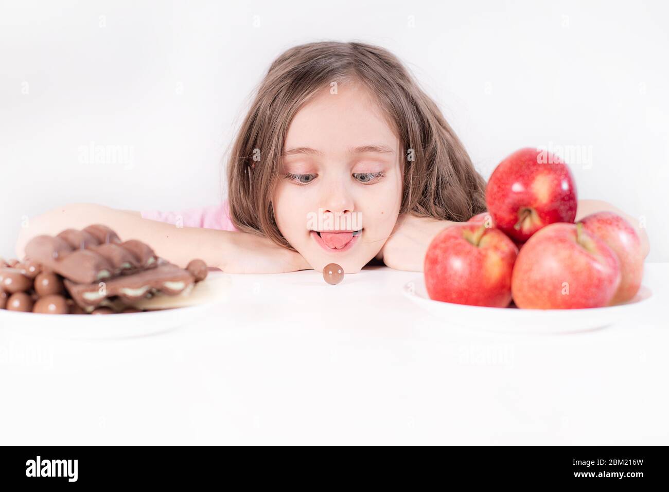 Children and chocolate. A cheerful girl chooses between chocolate and ...