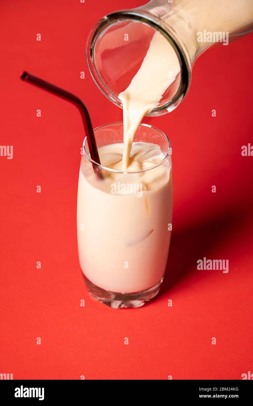 Pouring horchata, Mexican almond, and rice milk, in a glass with ice ...