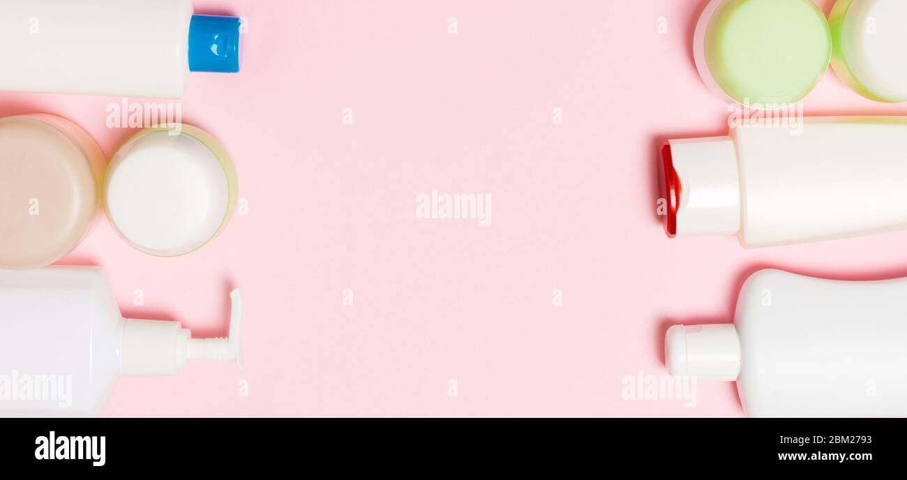 Top view of cosmetic containers, sprays, jars and bottles on pink ...