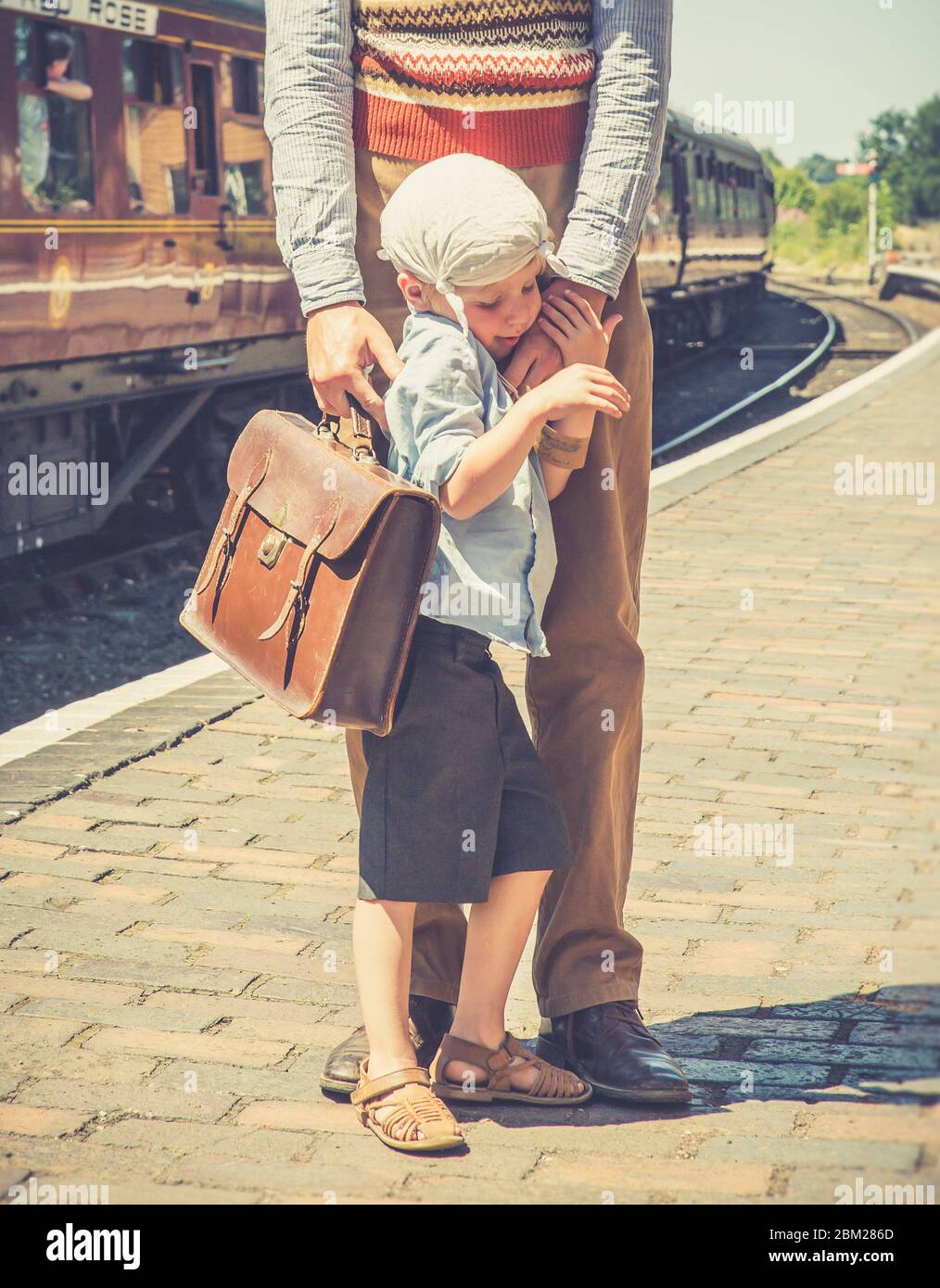 Anxious boy dressed in 1940s costume on platform of UK heritage steam ...