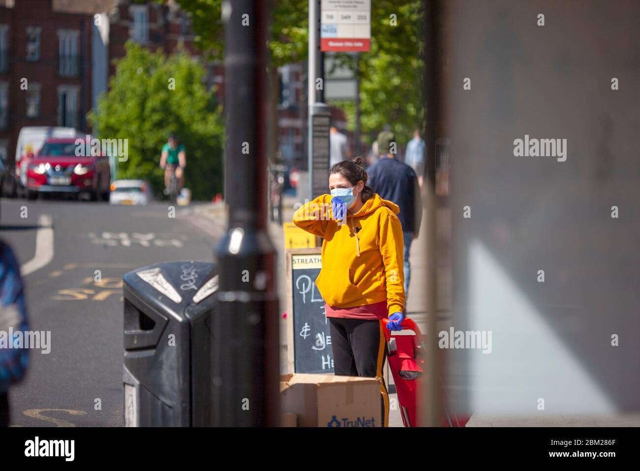 Woman stood at a London bus stop wearing personal protective equipment ...
