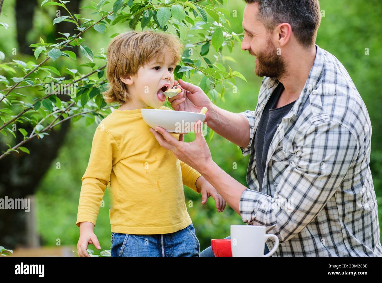 son and father eating outdoor. Morning breakfast. Tasty food. healthy ...