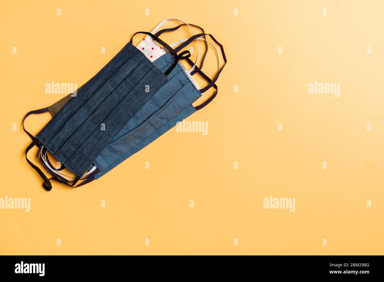 Top view of a heap of homemade cotton reusable masks on orange ...