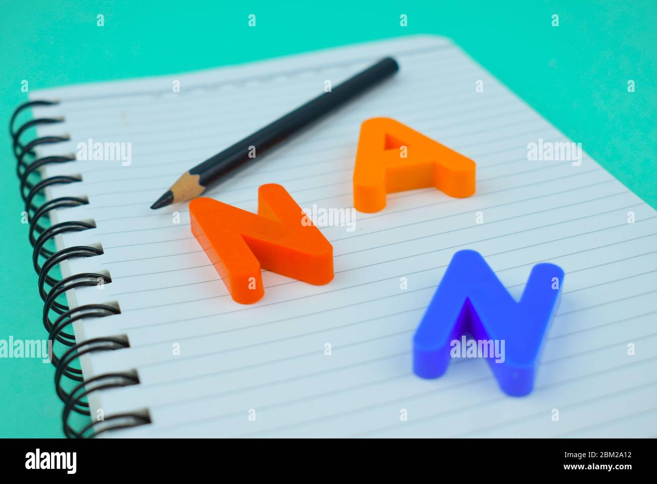 Three different colored letter blocks and a black pencil placed on a ...
