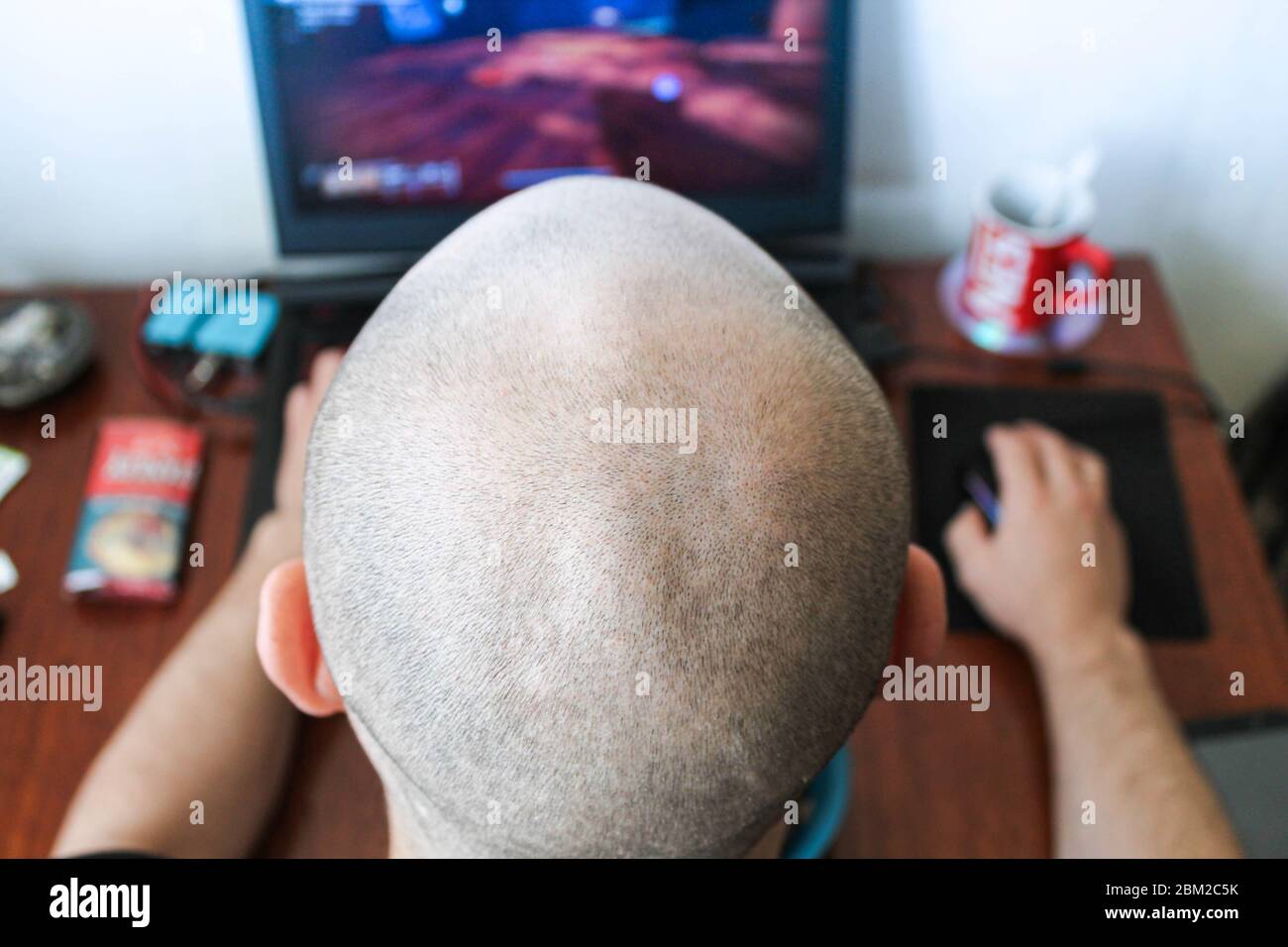 Rear view of a bald man playing a computer game Stock Photo - Alamy