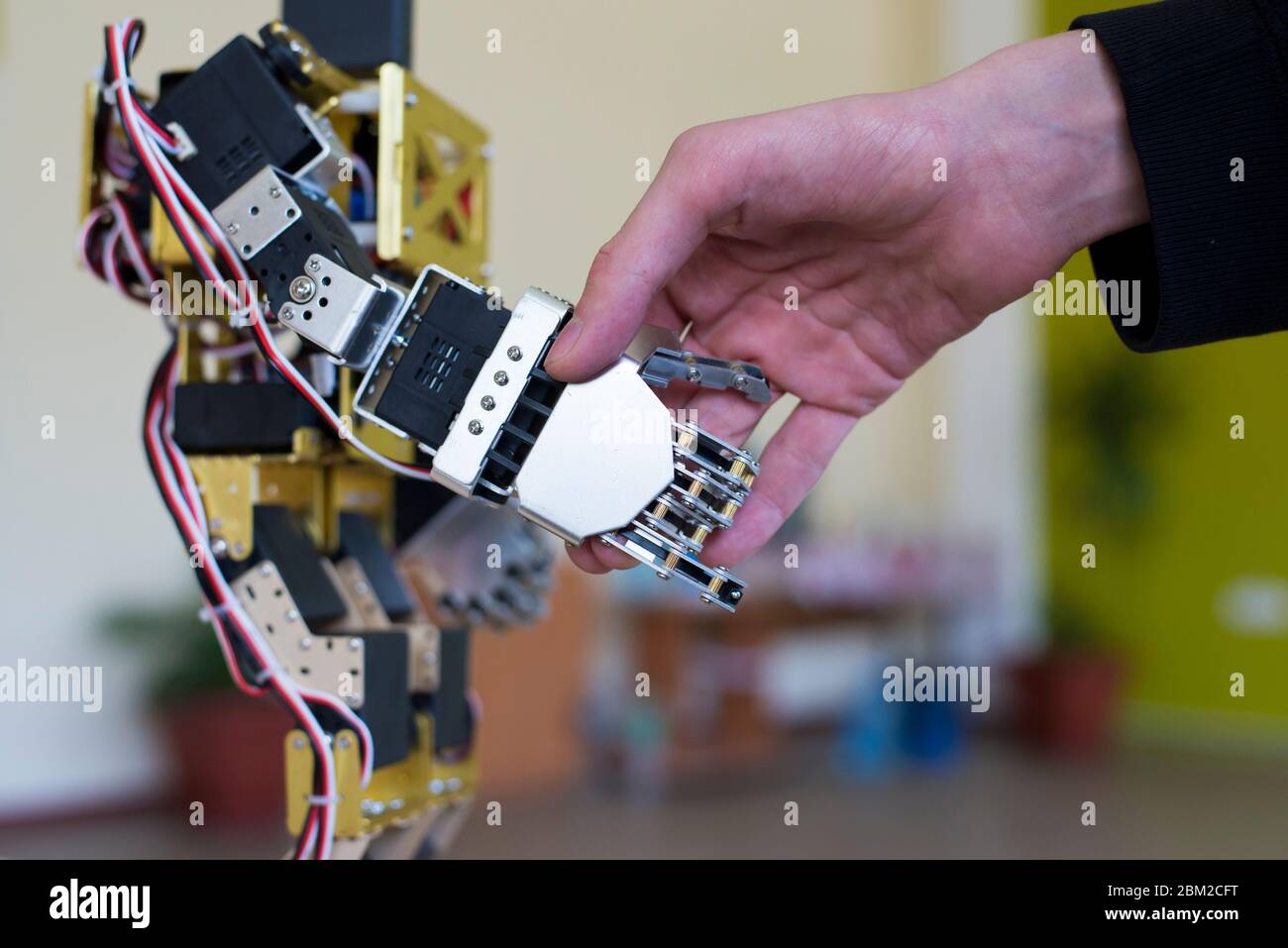 Photo of a human hand holding a robot hand with a handshake Stock Photo ...