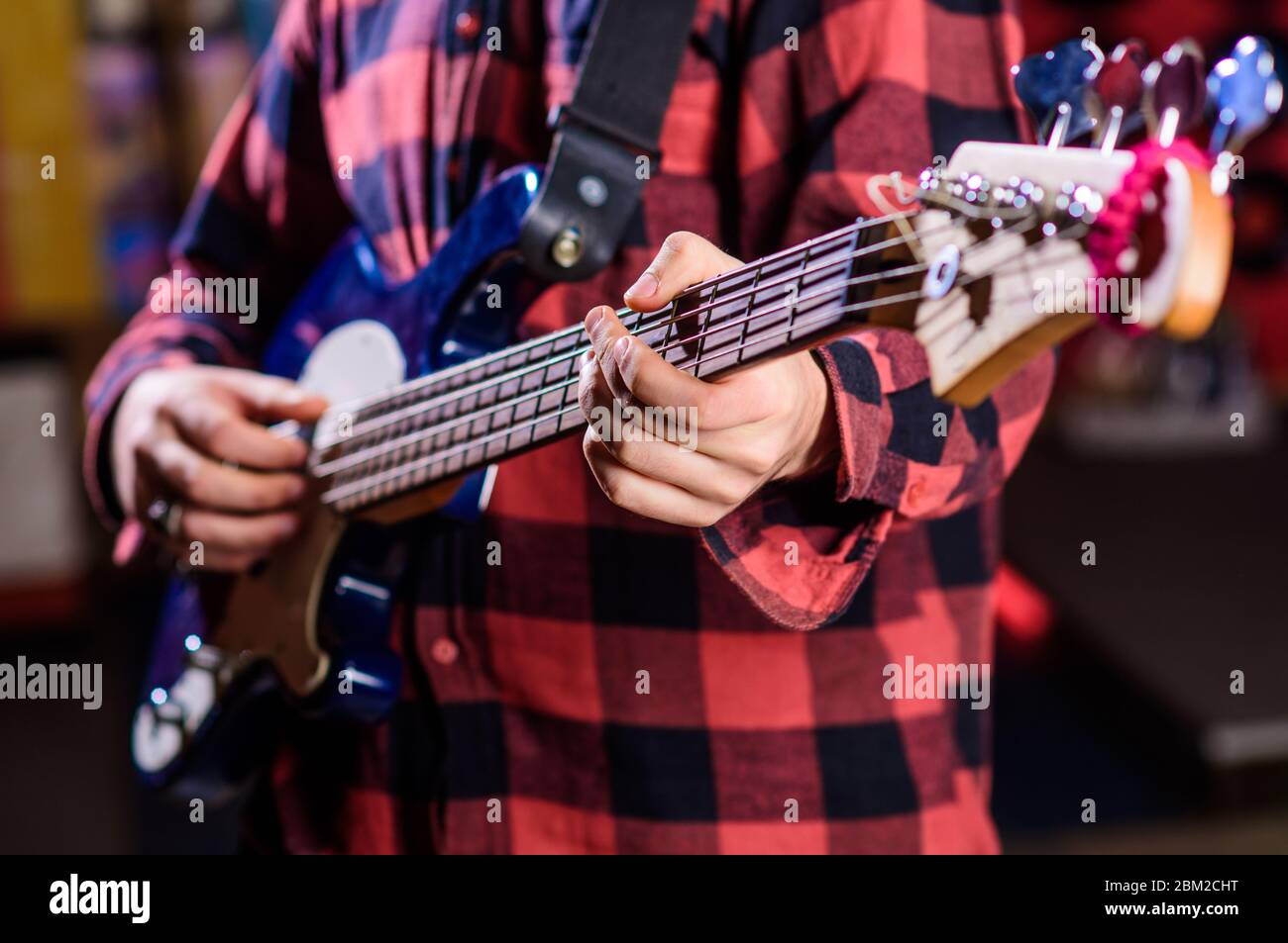 Male hands holds bass guitar, play music in club atmosphere background ...