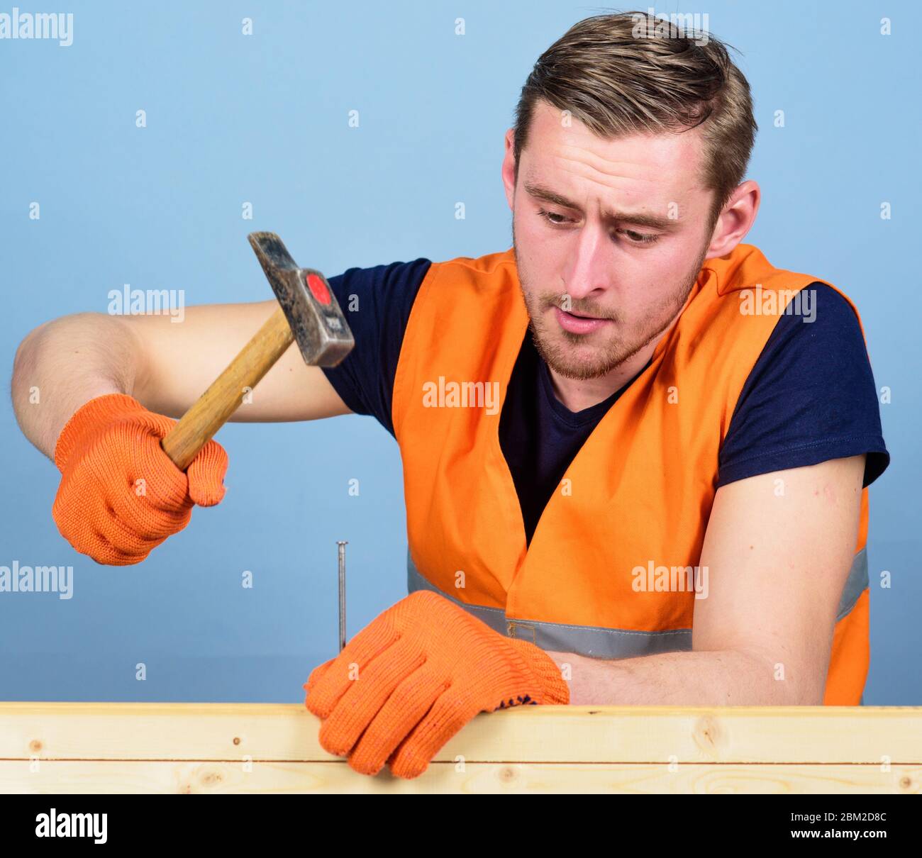 Carpenter, woodworker, builder on concentrated face hammering nail into ...