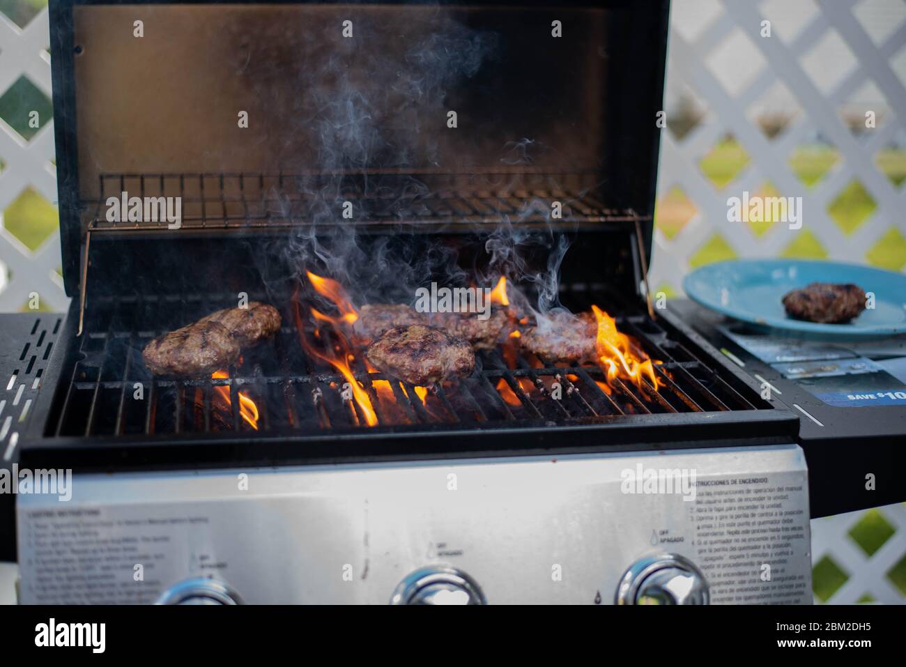 Hamburgers cooking on a grill in the summer with flames showing Stock ...