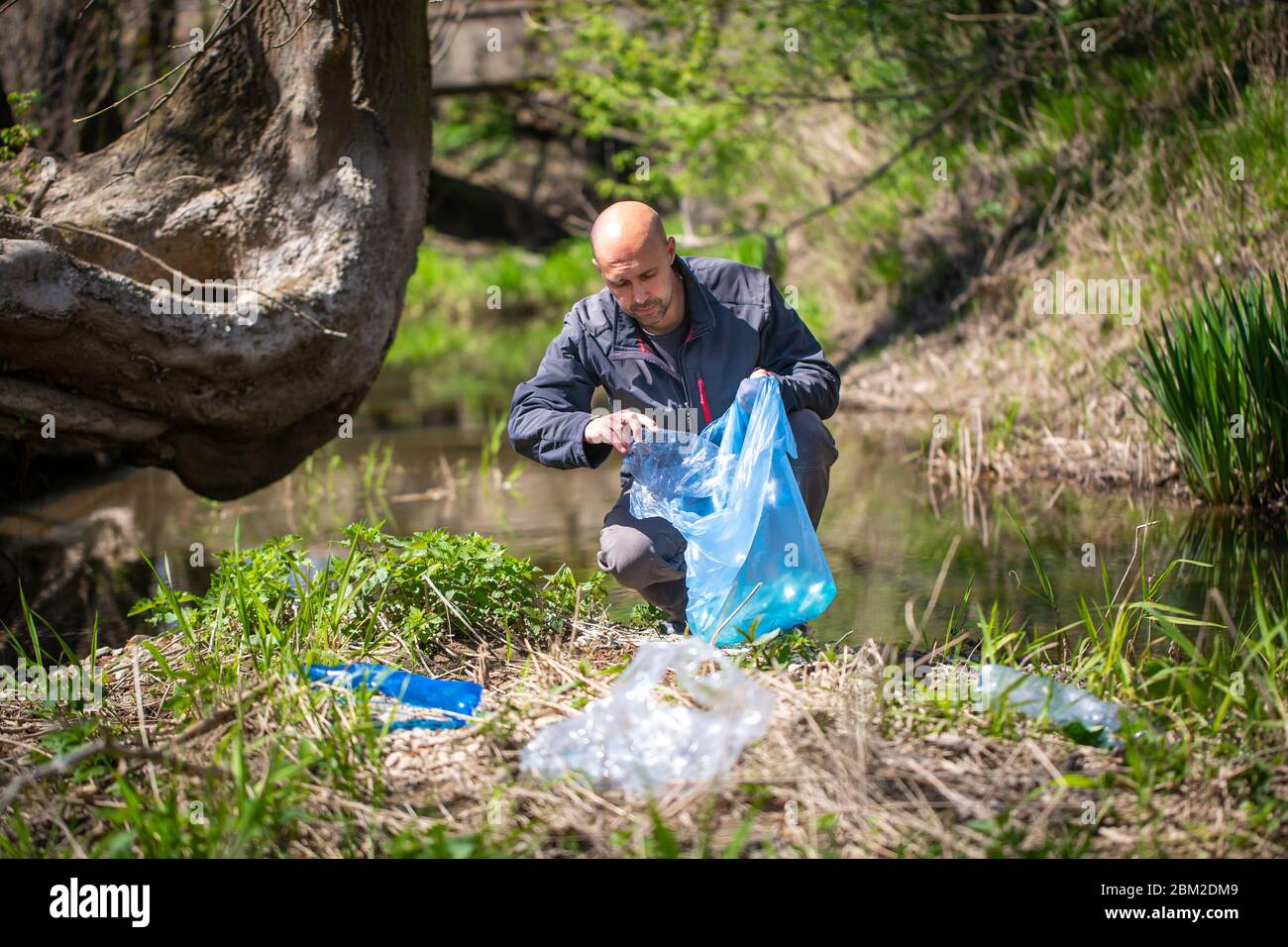 Man picking up plastic bottle, garbage collecting in the forest ...