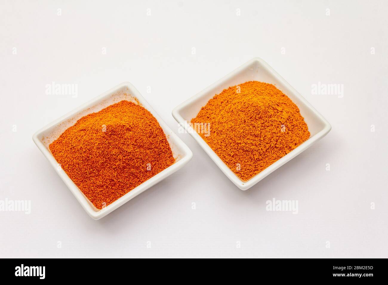 Two types of Hungarian paprika powder, hot and sweet, isolated on white ...