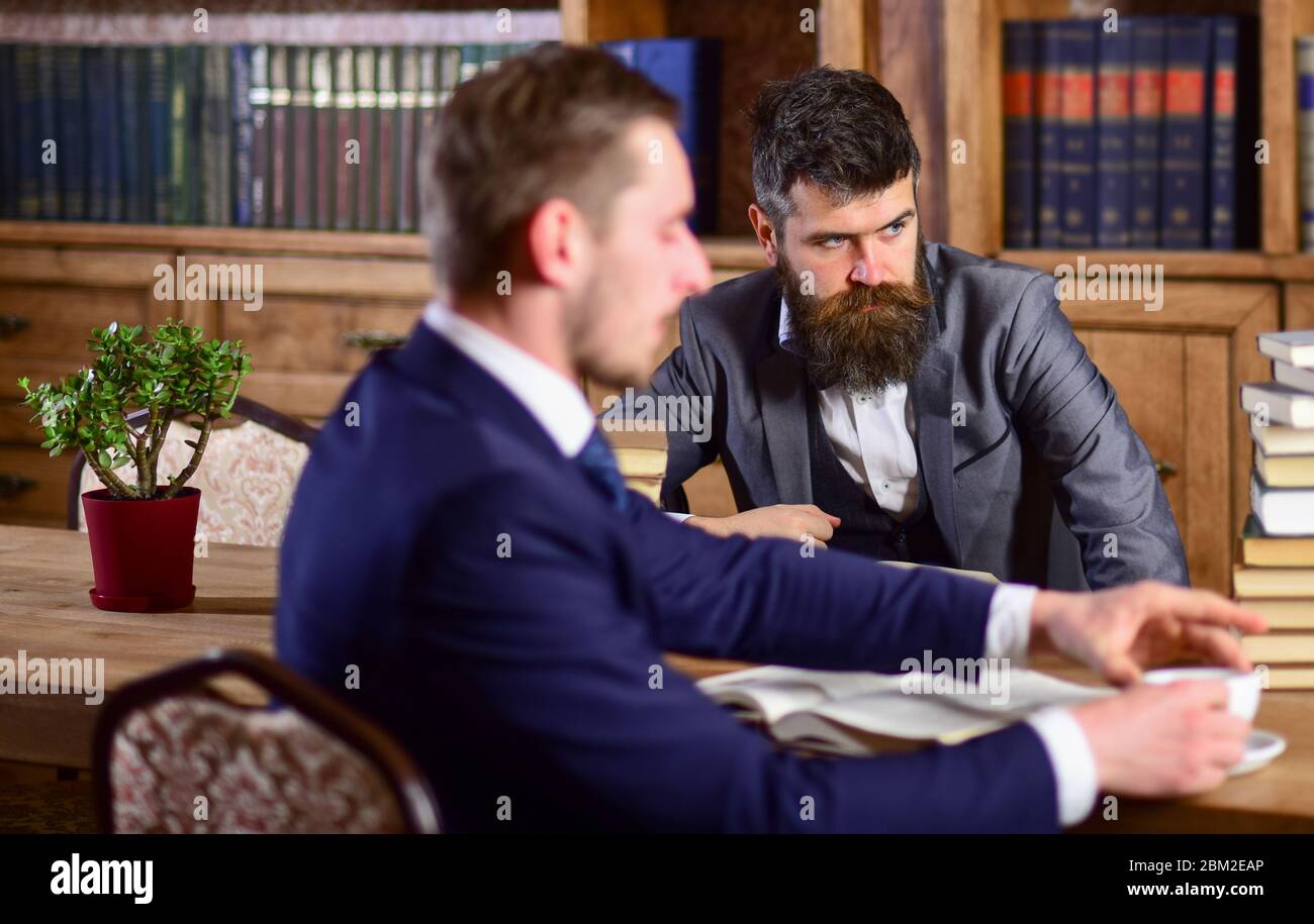 Men with serious faces in retro interior with bookshelves on background ...