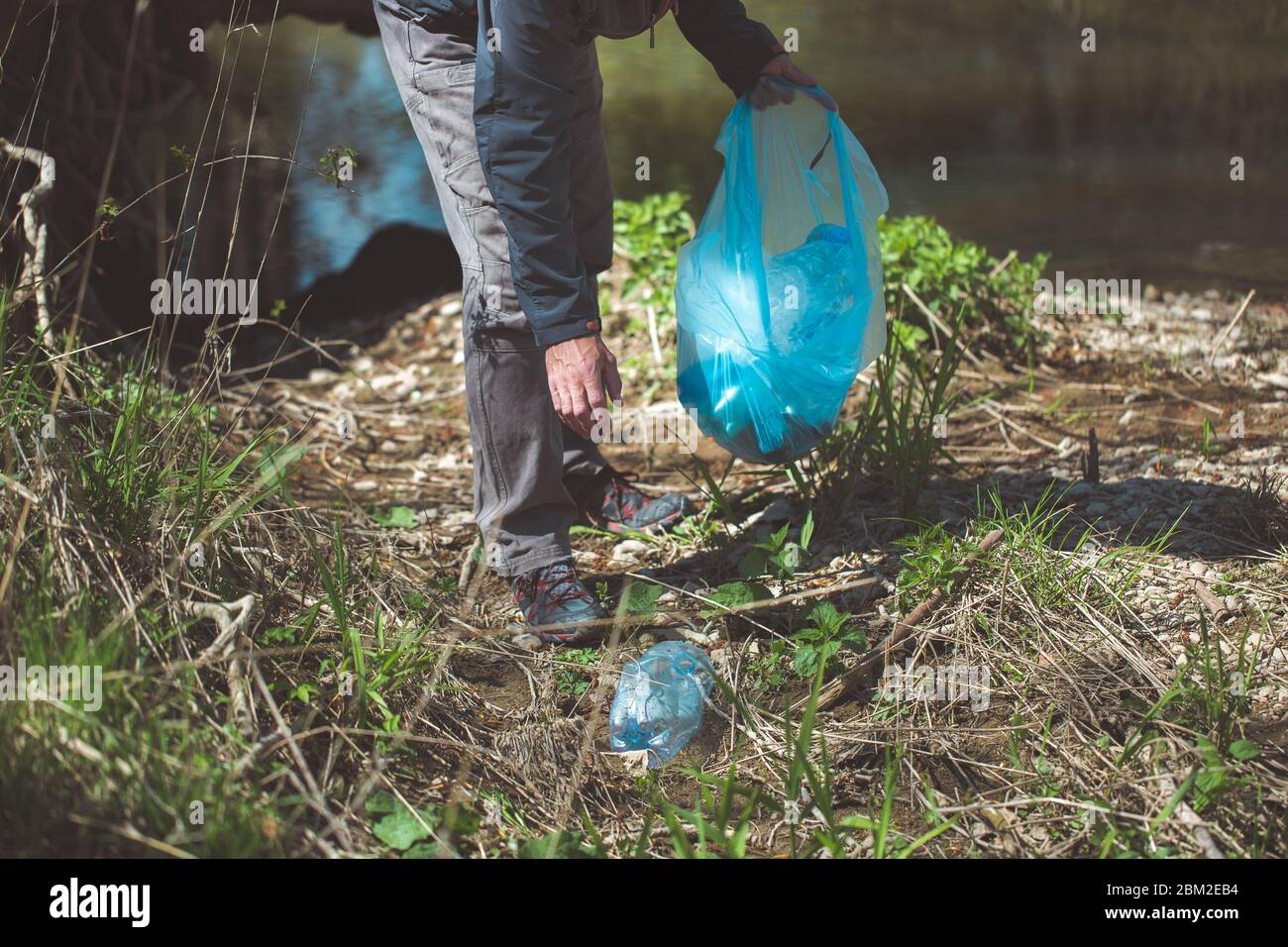 Man picking up plastic bottle, garbage collecting in the forest ...