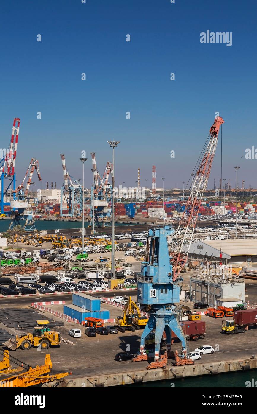 Four-link cargo loading crane on dock with parked motor vehicles ready ...