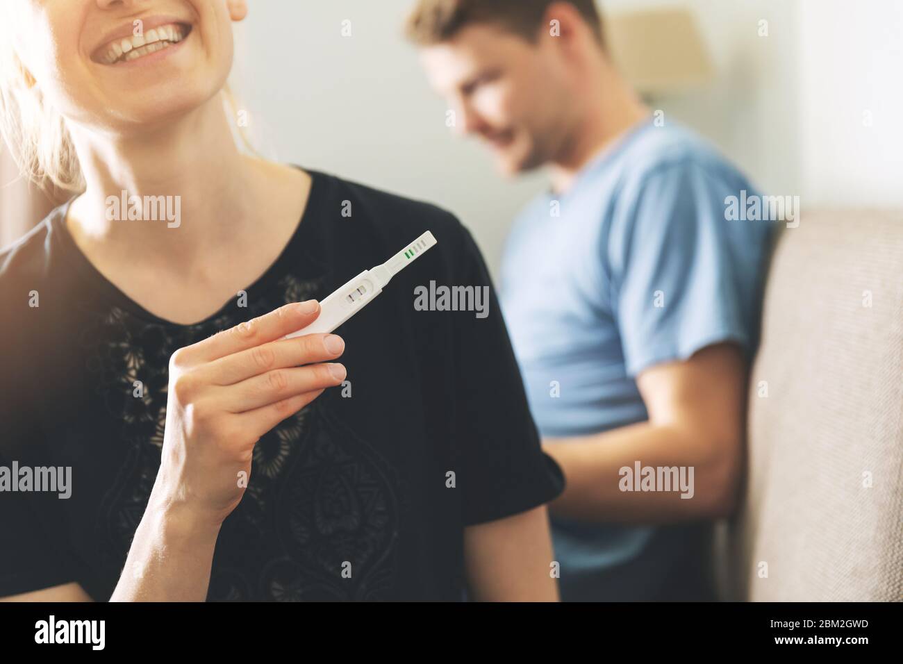 young happy woman sitting on couch at home and holding positive ...