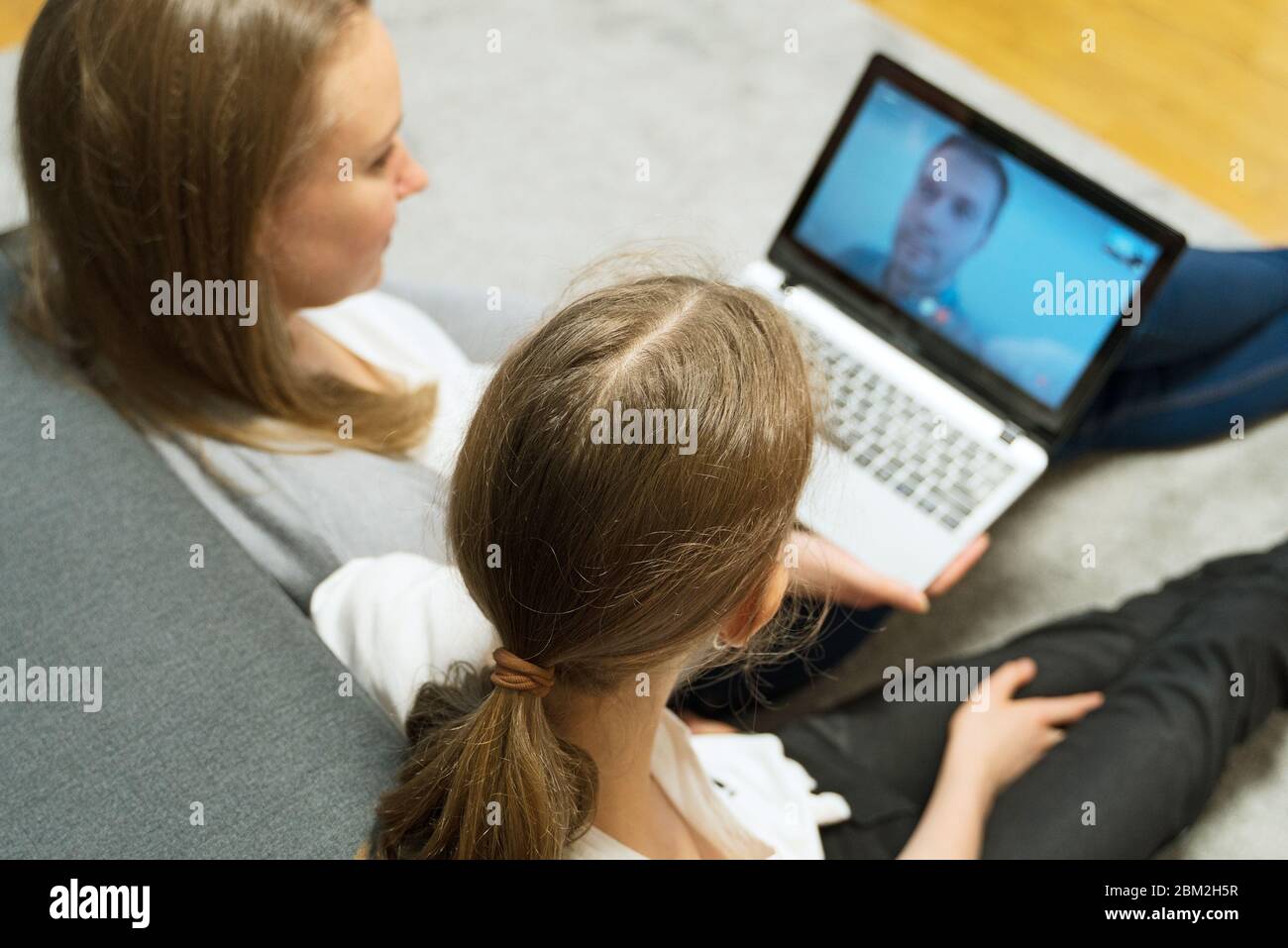 Woman and her daughter communicate with dad. Video call Stock Photo - Alamy