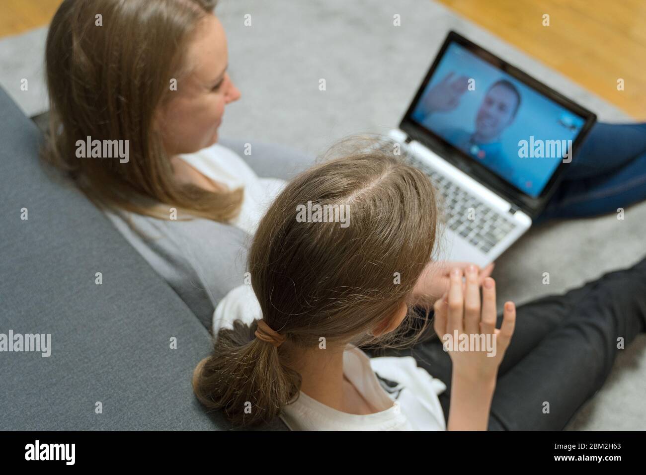 Woman and her daughter communicate with dad. Video call Stock Photo - Alamy