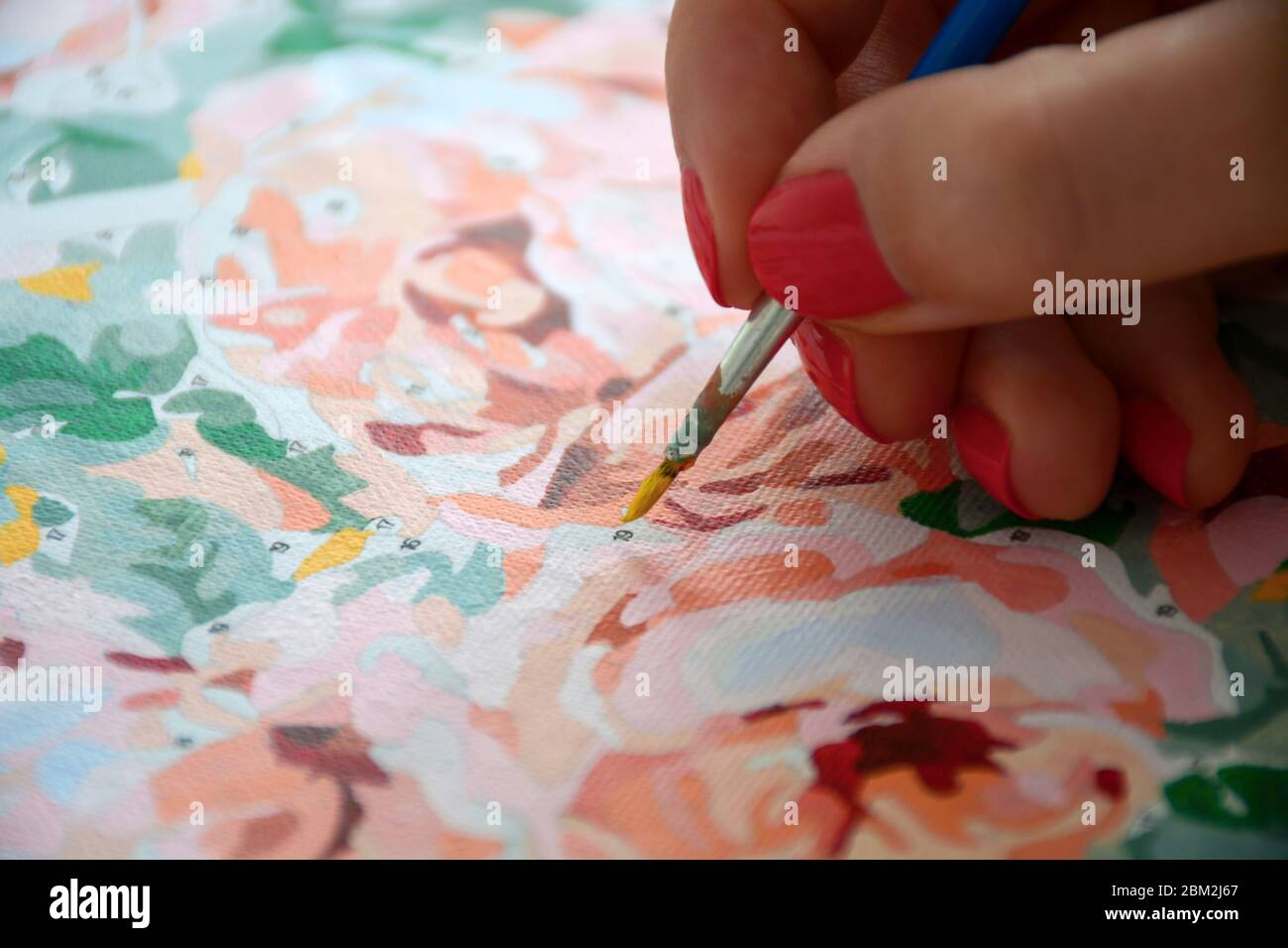 Close up painting by numbers. Woman's hand drawing on numbered canvas ...