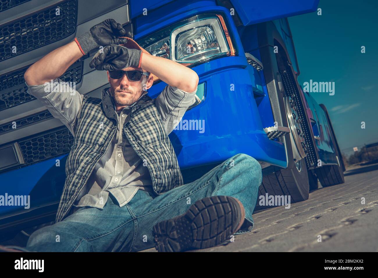 Semi Truck Male Driver Outside Of Vehicle Sitting On Ground Relaxing ...