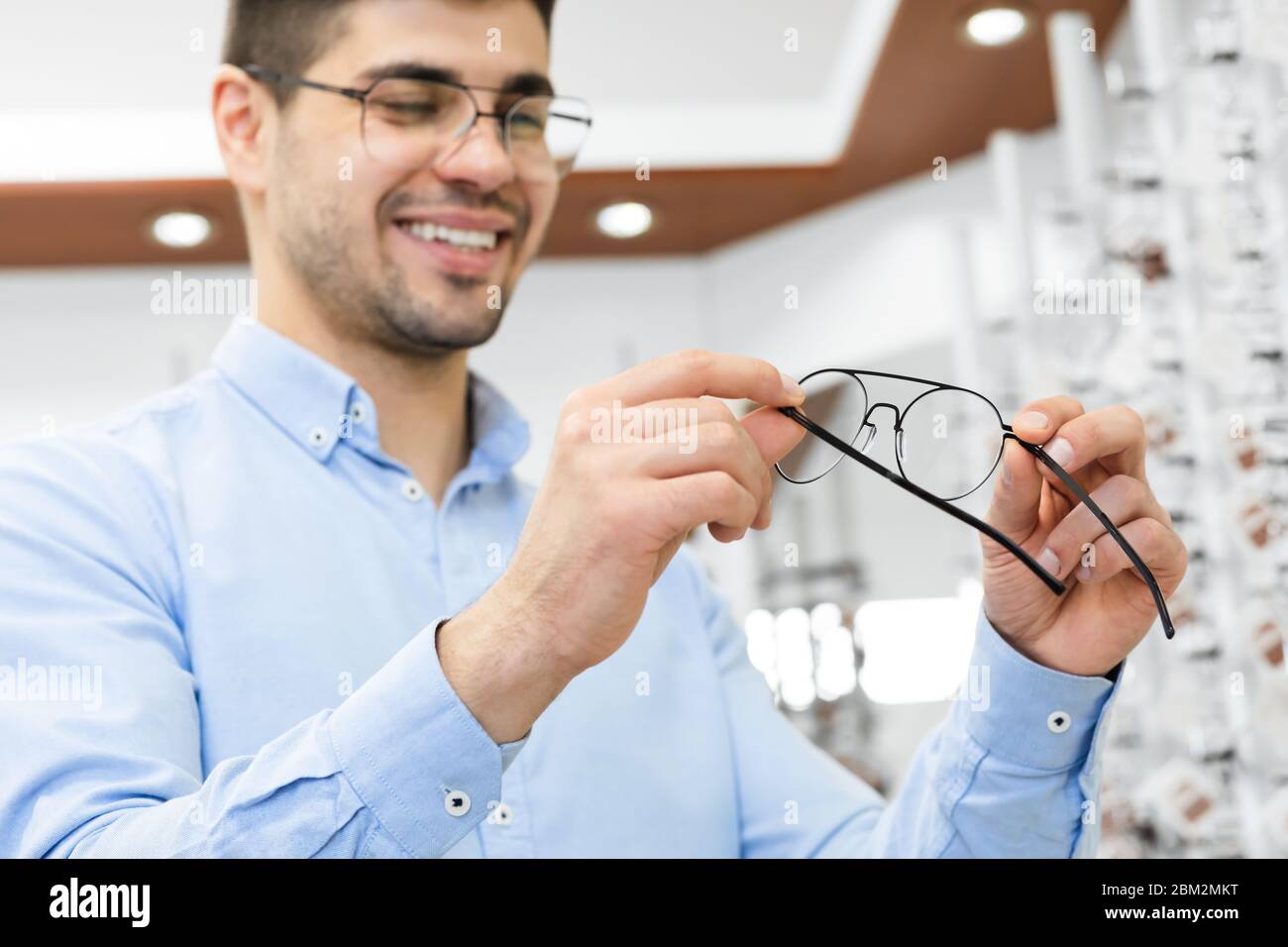 Portrait of handsome young guy choosing spectacles Stock Photo - Alamy