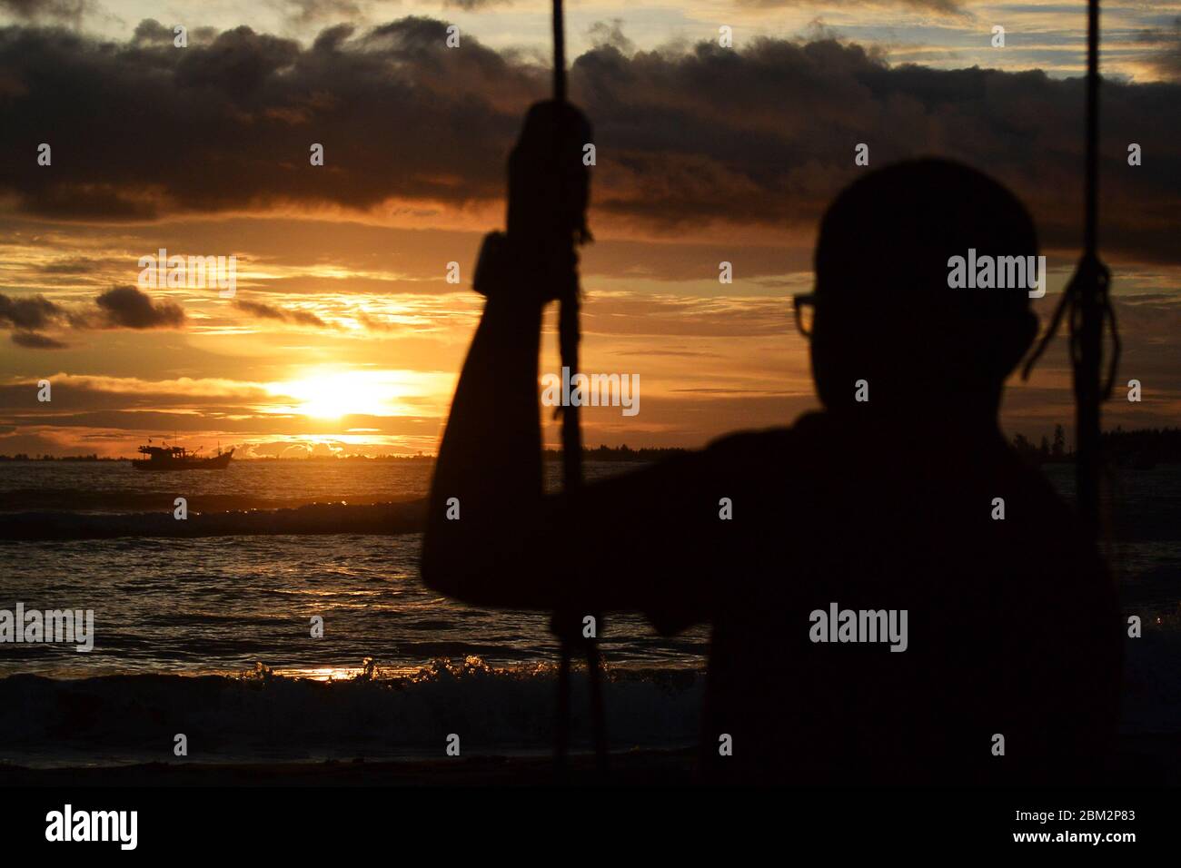 Susoh, Aceh, Indonesia. 6th May, 2020. Silhouette of a man on a swing ...