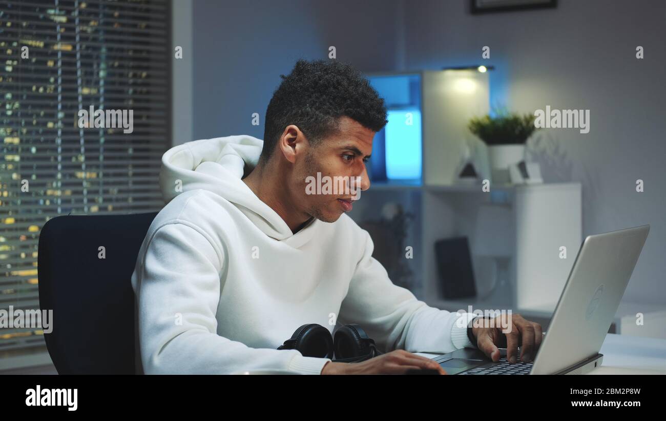 Sad black gamer in headphones lost online game on computer late at ...
