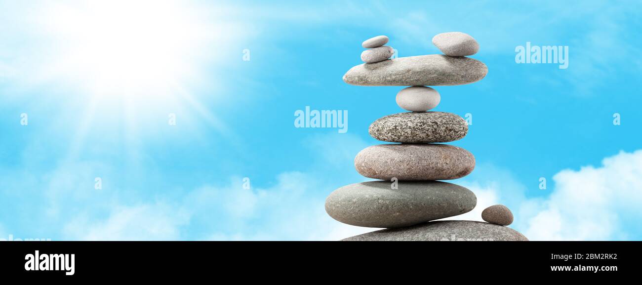 Pyramid of sea pebbles over a sunny sky. Life balance and harmony ...