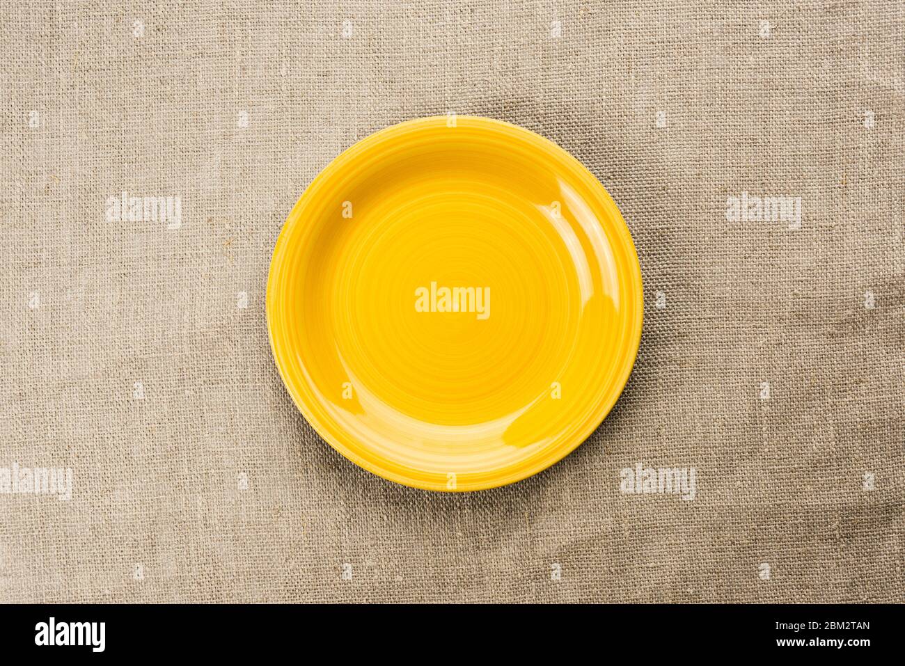 Yellow plate on canvas, top view Stock Photo - Alamy
