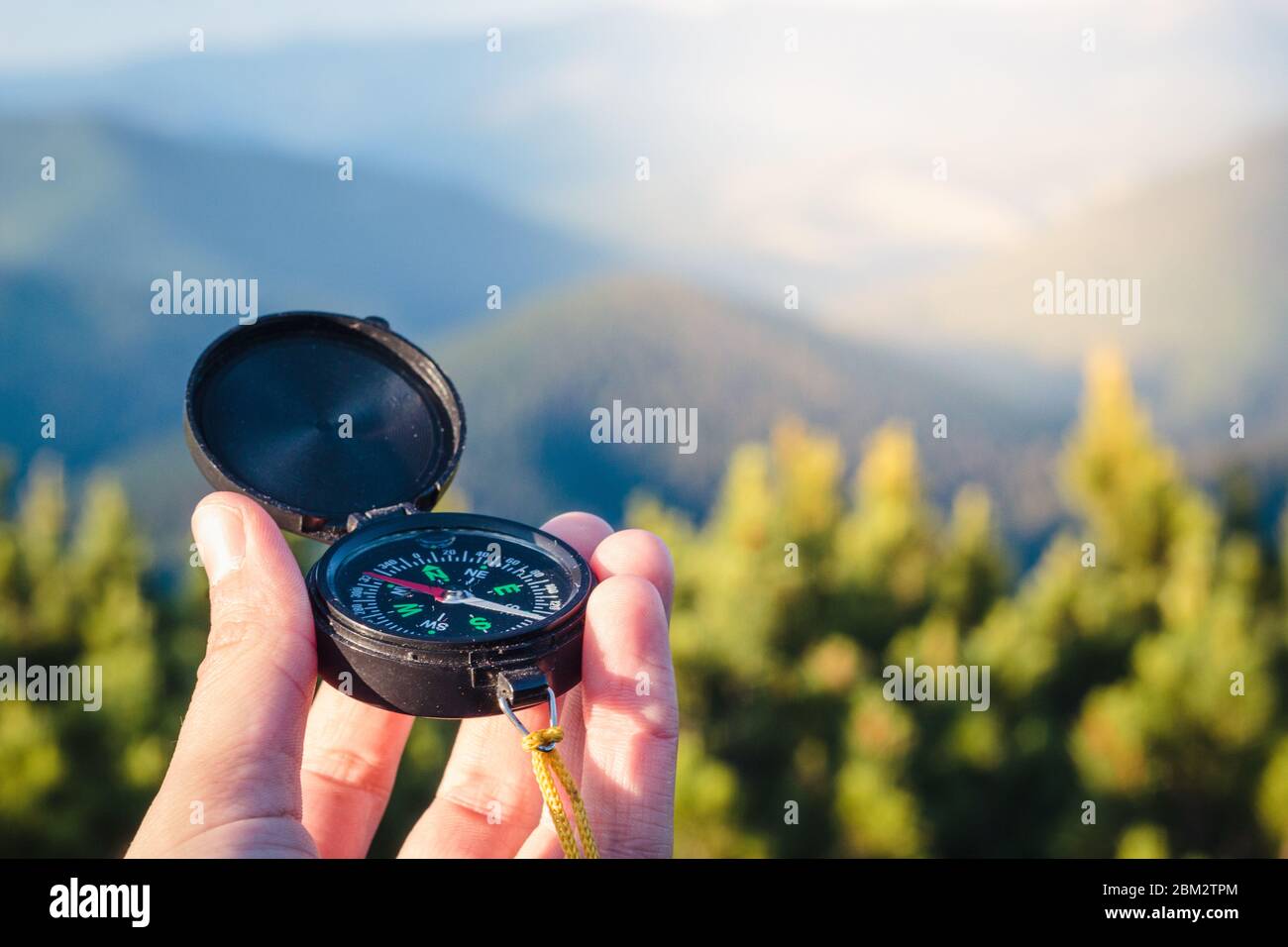 Hand holding compass on summer mountains background Stock Photo - Alamy