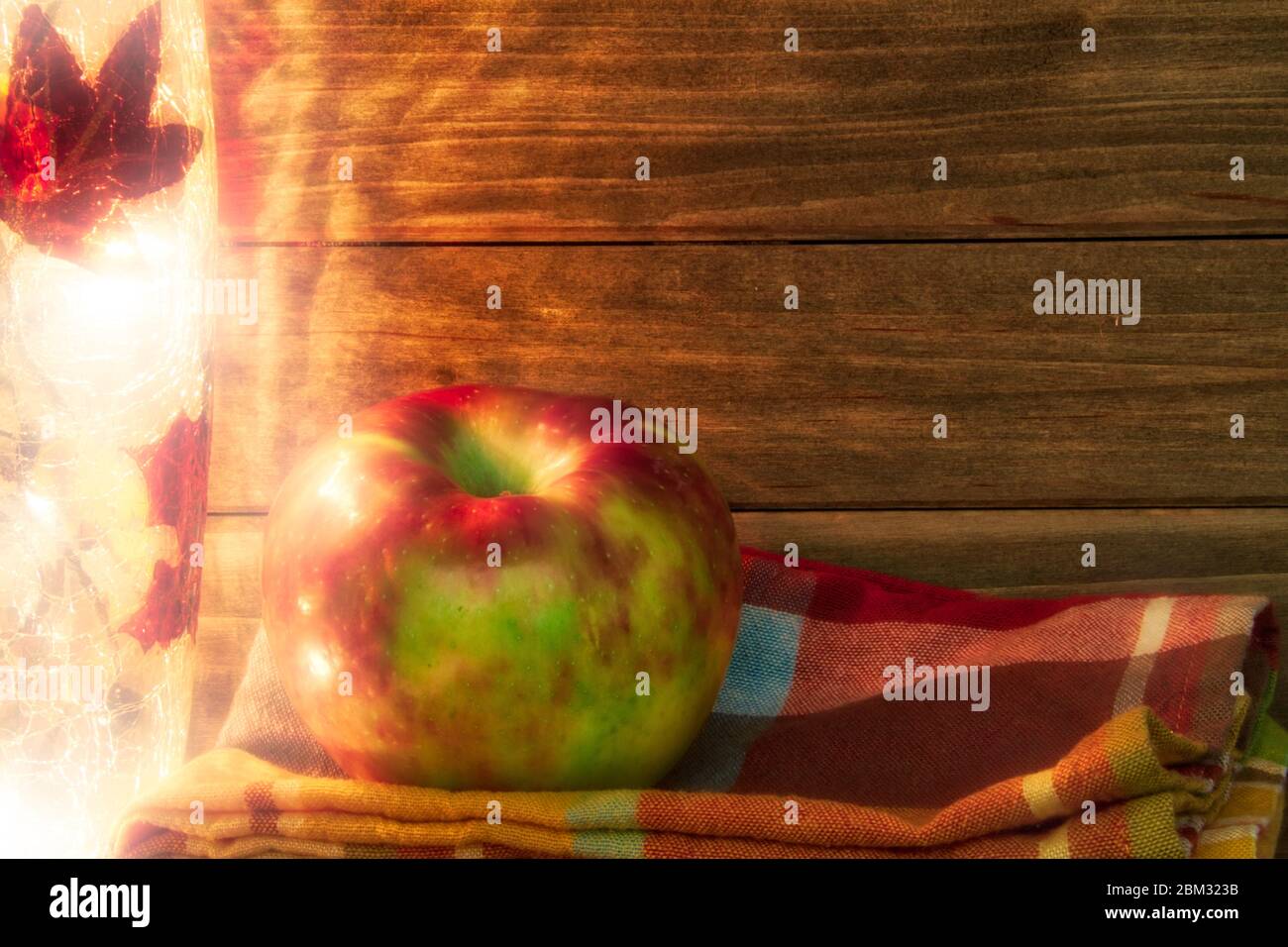 Apple in a fall theme with light and napkin and a wood background ...