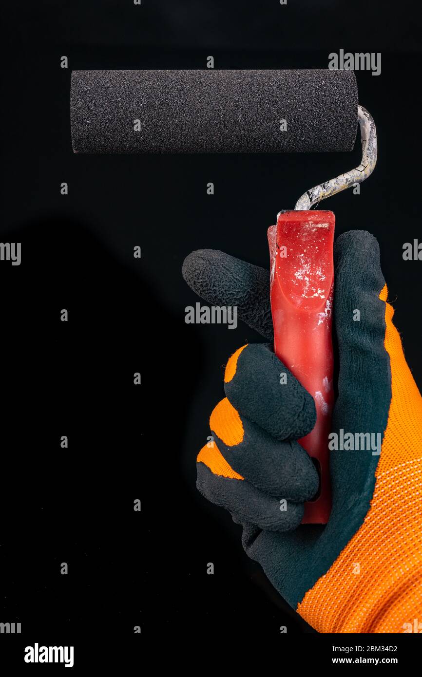 Paint roller in hand. Painting oil paint on flat surfaces. Dark ...