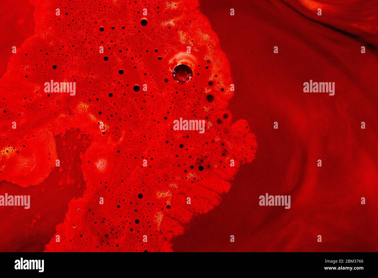 Spilled red paint with blisters and streaks. Close-up of the red spot ...