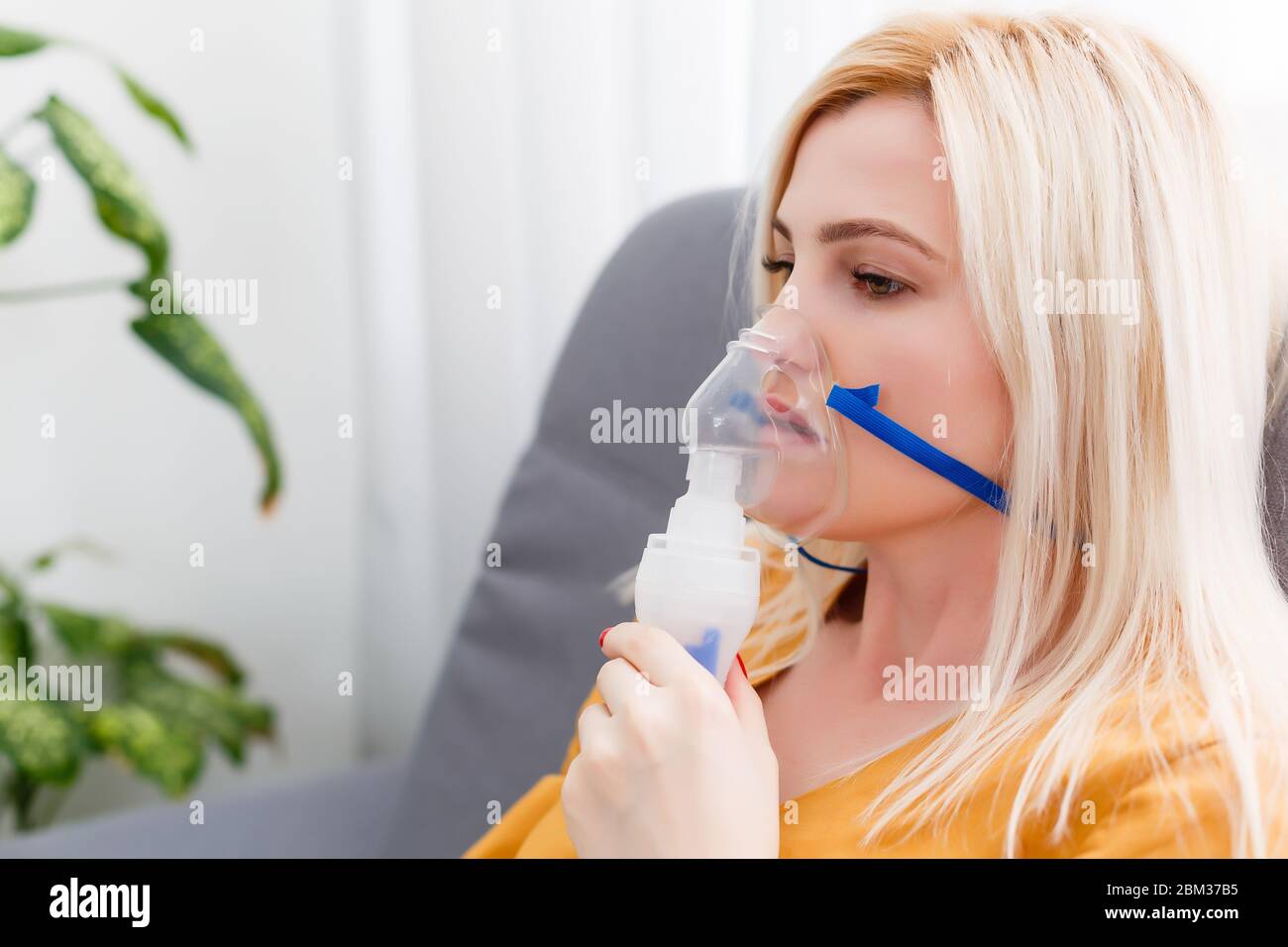 woman makes inhalation nebulizer at home. holding a mask nebulizer ...