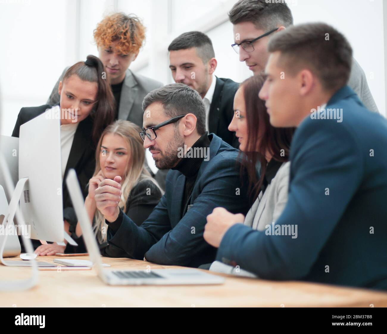 team of young employees looking together at a computer screen Stock ...