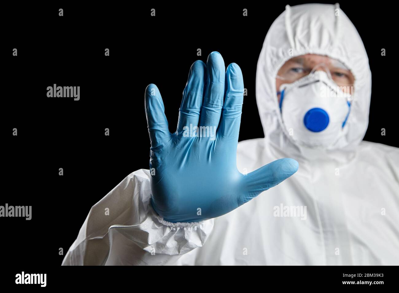 Man in white protective suit showing stop gesture, isolated on black ...