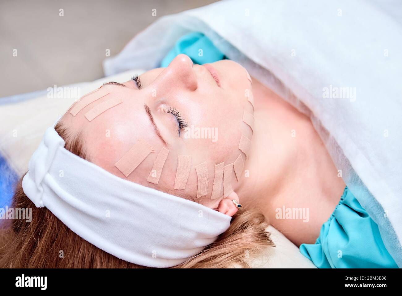 aping. Caucasian woman lying with tape on her face. Physiotherapy and ...