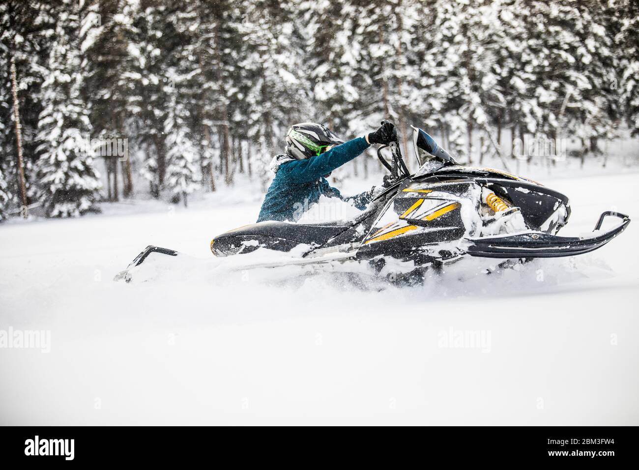 Side view of man turning snowmobile in deep powder Stock Photo - Alamy