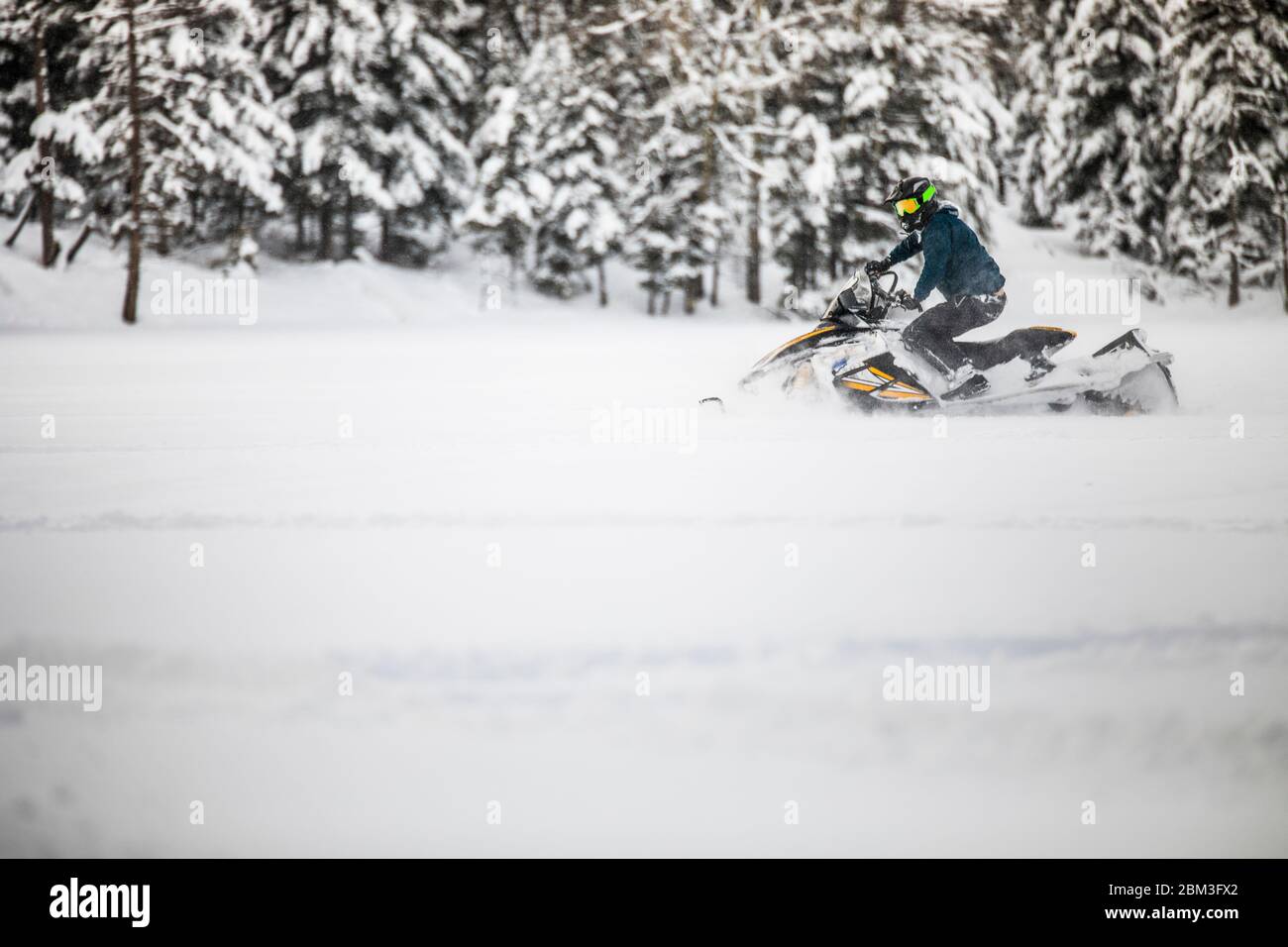 active man snowmobiling through deep snow during weekend getaway Stock ...